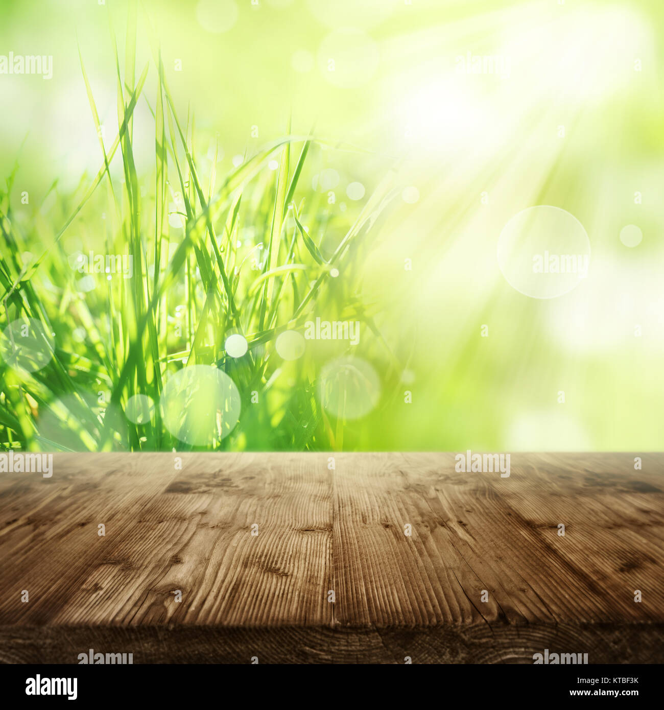 Spring background with green grass in front of an empty rustic wooden ...