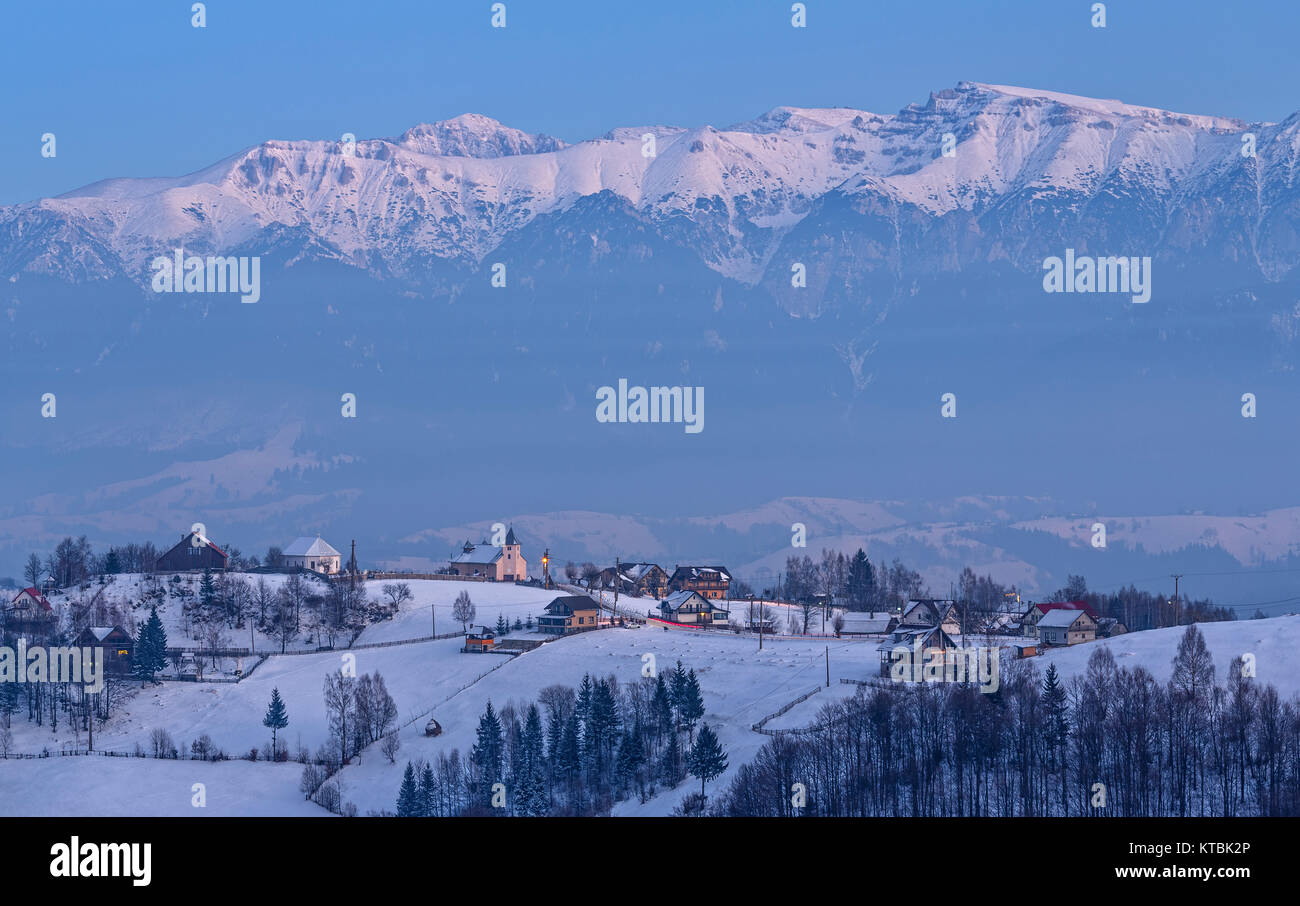 Evening fall over snowy Pestera village in the frozen valleys of Bucegi ...