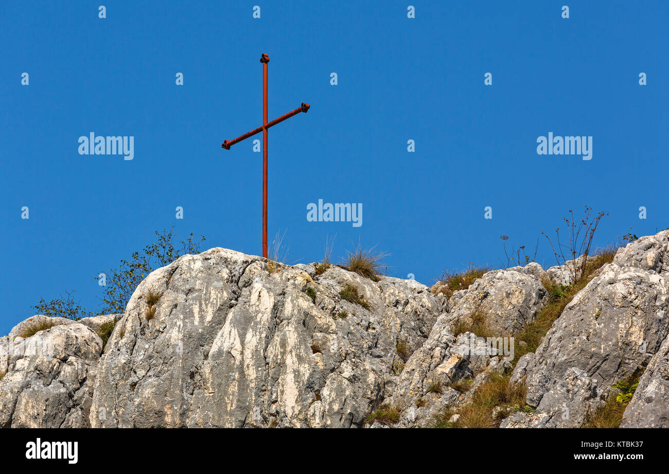Red iron cross on top of mountain rocks, over clear blue sky Stock ...
