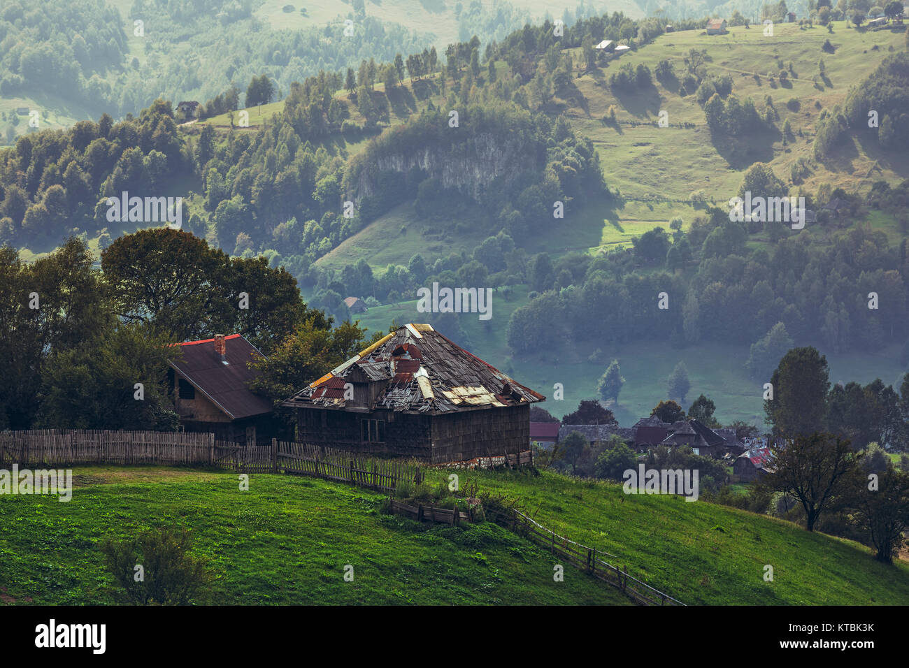 Rural landscape with traditional Romanian wooden houses uphill in ...