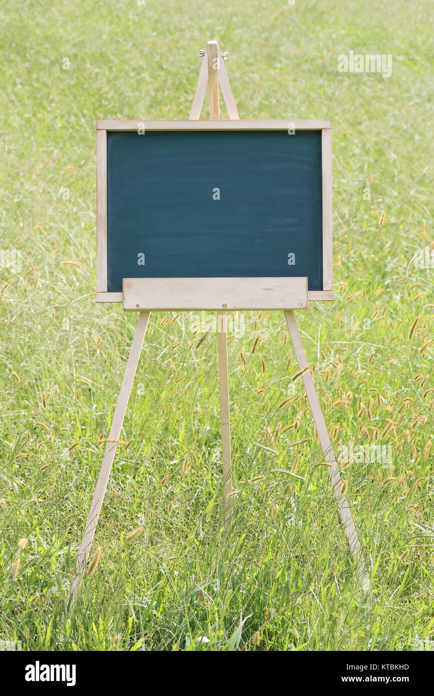 empty chalkboard with wooden easel on green field background Stock ...