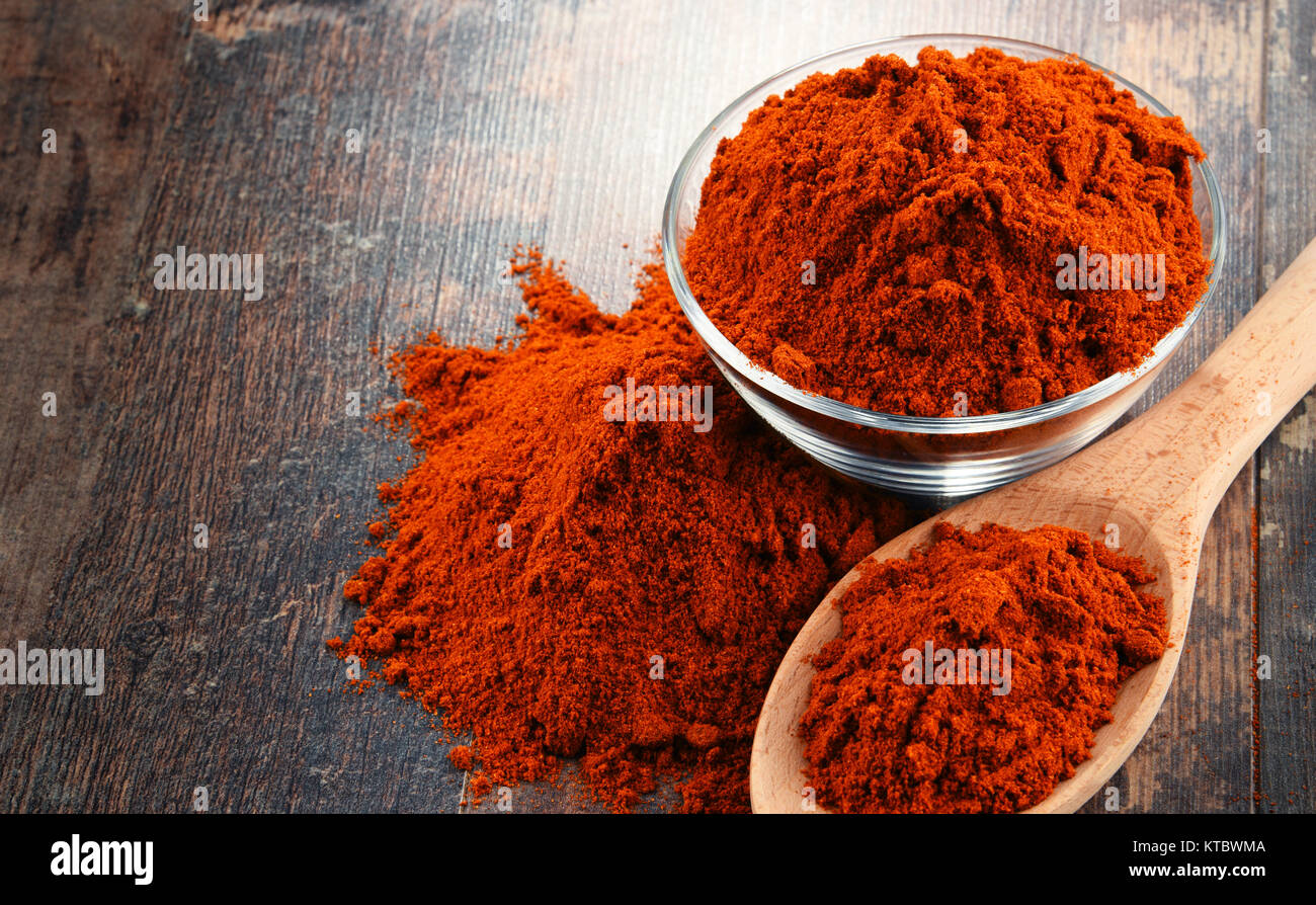 Composition with bowl of chili powder on wooden table Stock Photo - Alamy