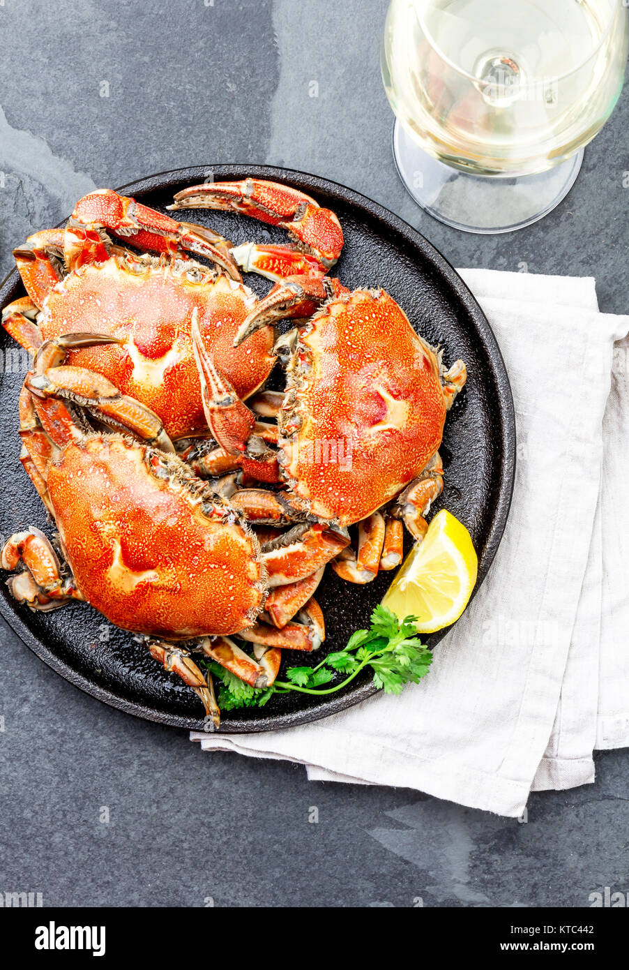 Cooked crabs on black plate served with white wine, black slate ...