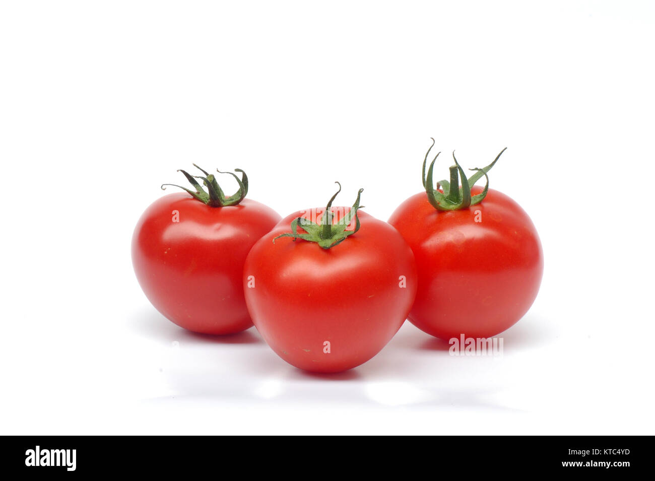three tomatoes on white background Stock Photo - Alamy