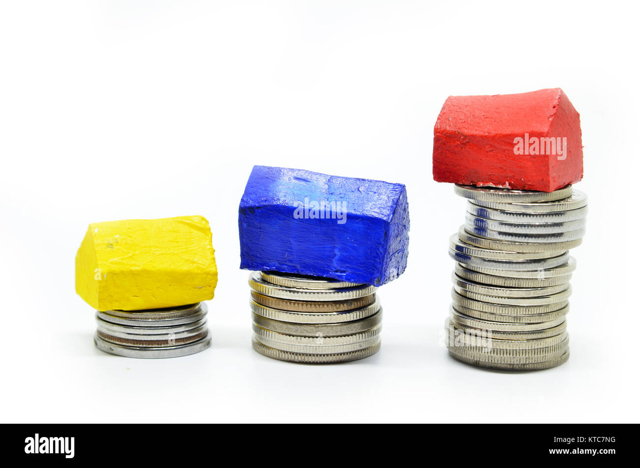 Coins stacked up in piles with color house Stock Photo - Alamy