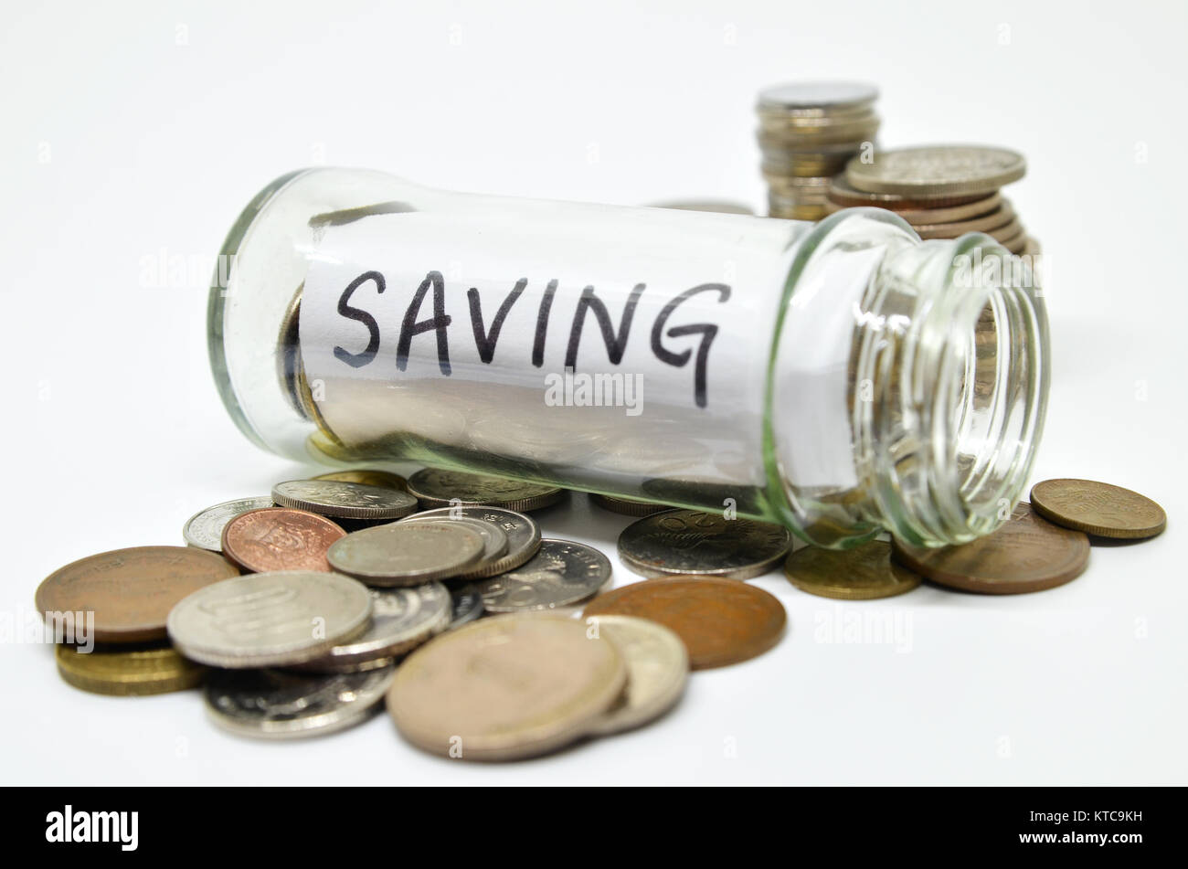 Saving lable in a glass jar with coins spilling out Stock Photo - Alamy