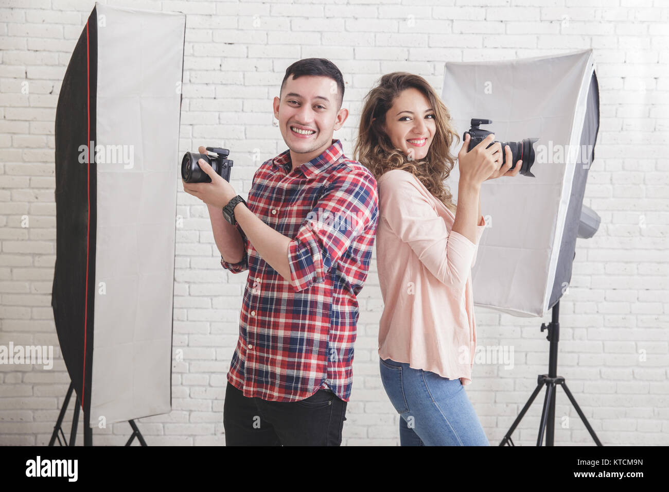 two young photographers back to back smiling while looking at ca Stock ...