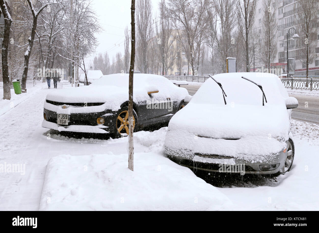 City after blizzard. Cars parked on a street of Kyiv covered with snow ...