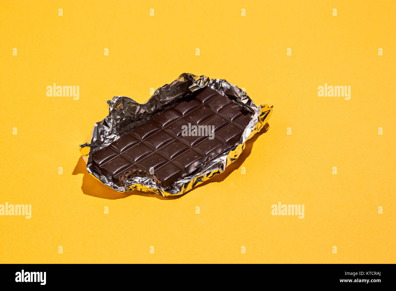 Bitten Chocolate bar in foil isolated on yellow background Stock Photo ...