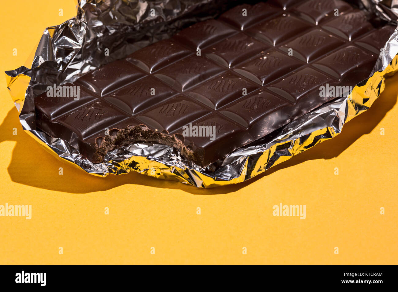 Bitten Chocolate bar in foil isolated on yellow background Stock Photo ...