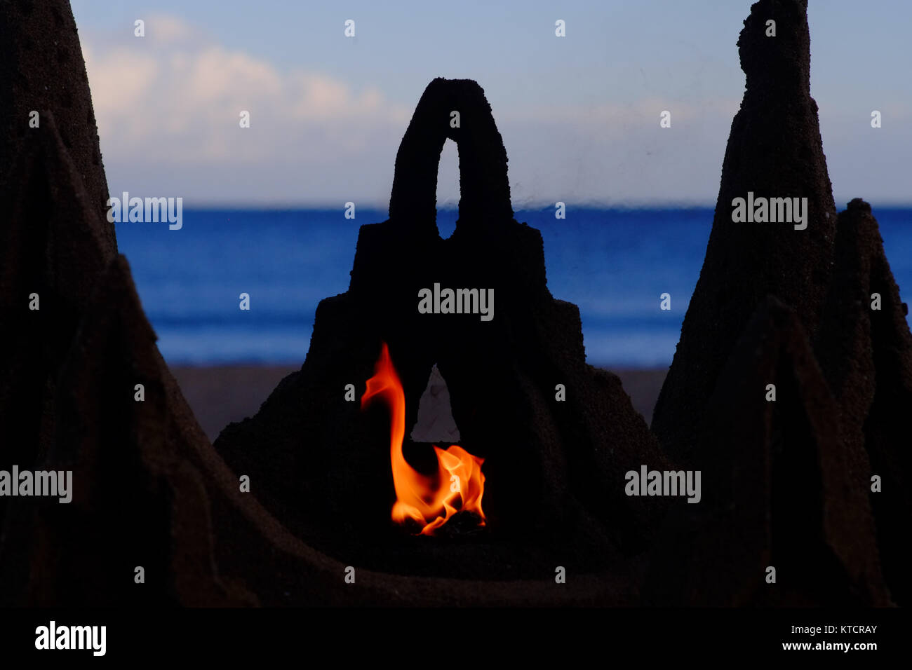 Fire prehistoric animal heating a sand castle in front of the beach ...
