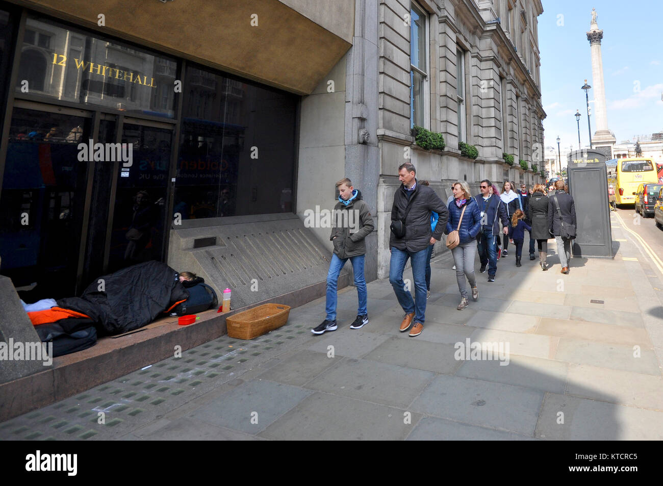 Homeless person sleeping on London street with passers by. Rough ...