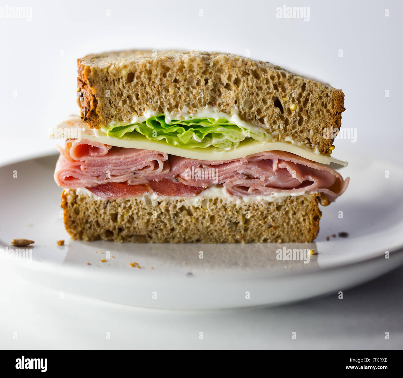 Ham sandwich made with artisan bread on a white plate. Copy space ...