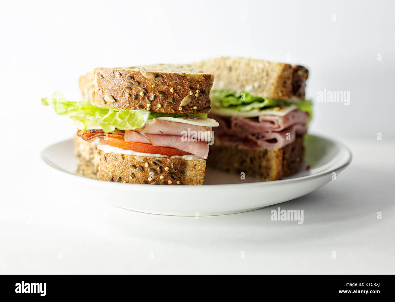 Ham sandwich made with artisan bread on a white plate. Copy space ...