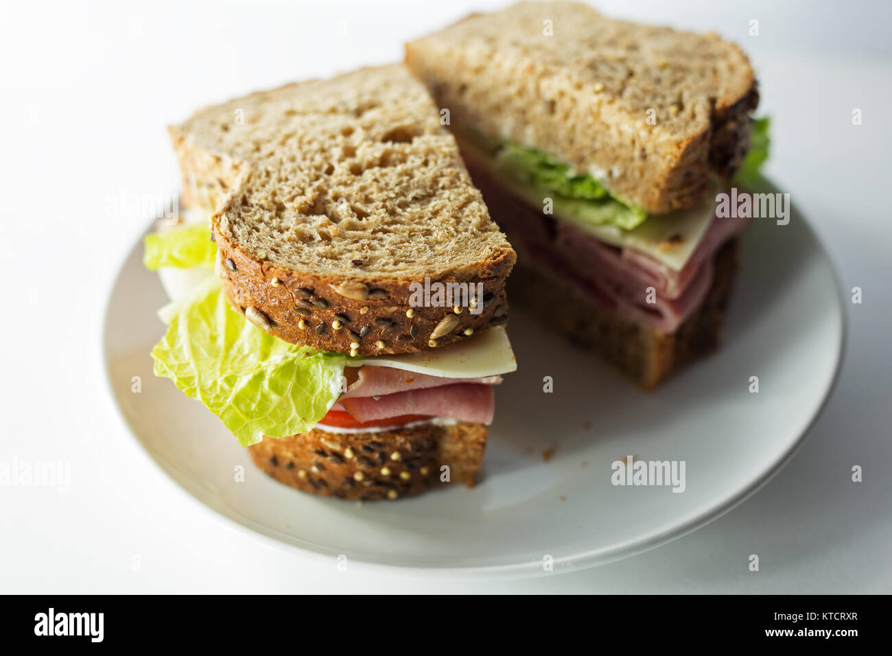 Ham sandwich made with artisan bread on a white plate. Copy space ...