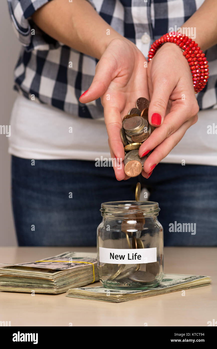 Young woman pouring coins into a jar. She is saving money to start a ...