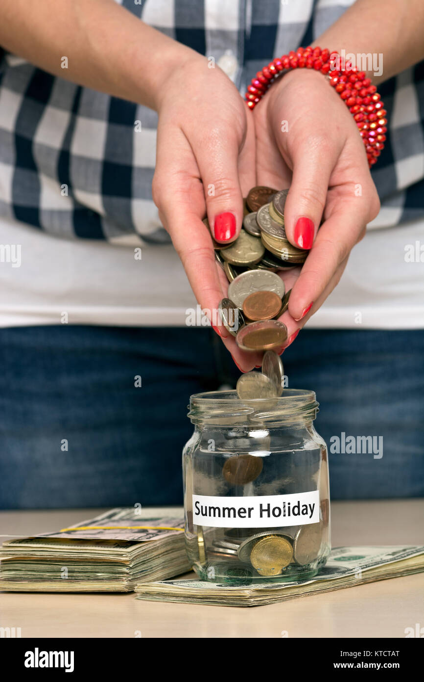 Young woman pouring coins into a jar. She is saving money for summer ...