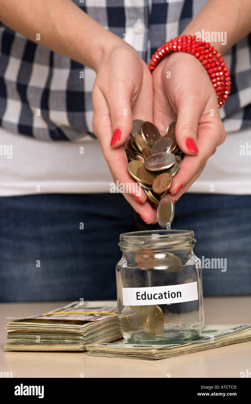 Young woman pouring coins into a jar. She is saving money for better ...