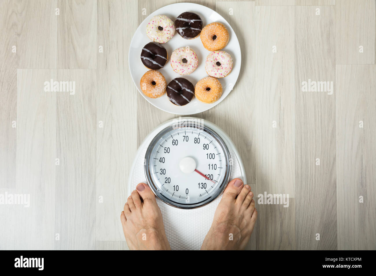Dish Of Donuts And Person Measuring His Weight Stock Photo - Alamy