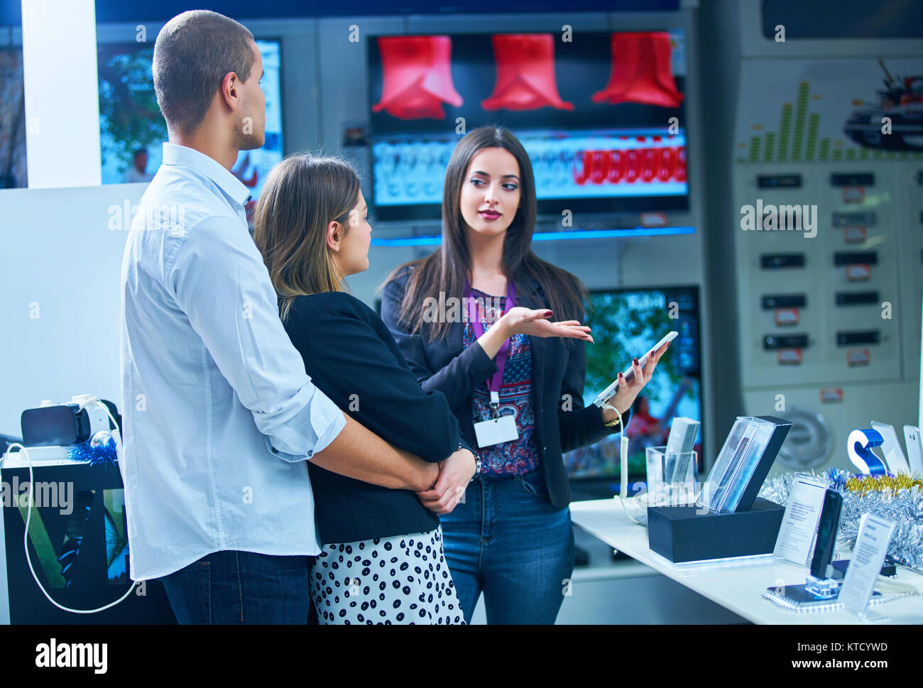 Young couple in consumer electronics store looking at latest laptop ...