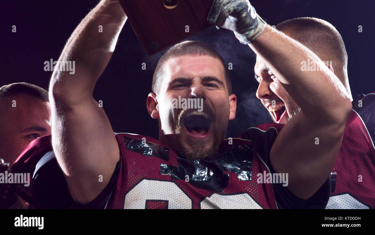 happy american football team celebrating victory with trophy and ...