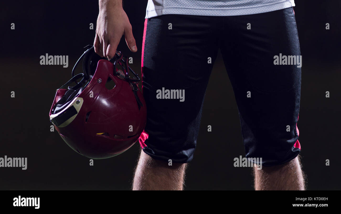 portrait of young confident American football player on field at night ...