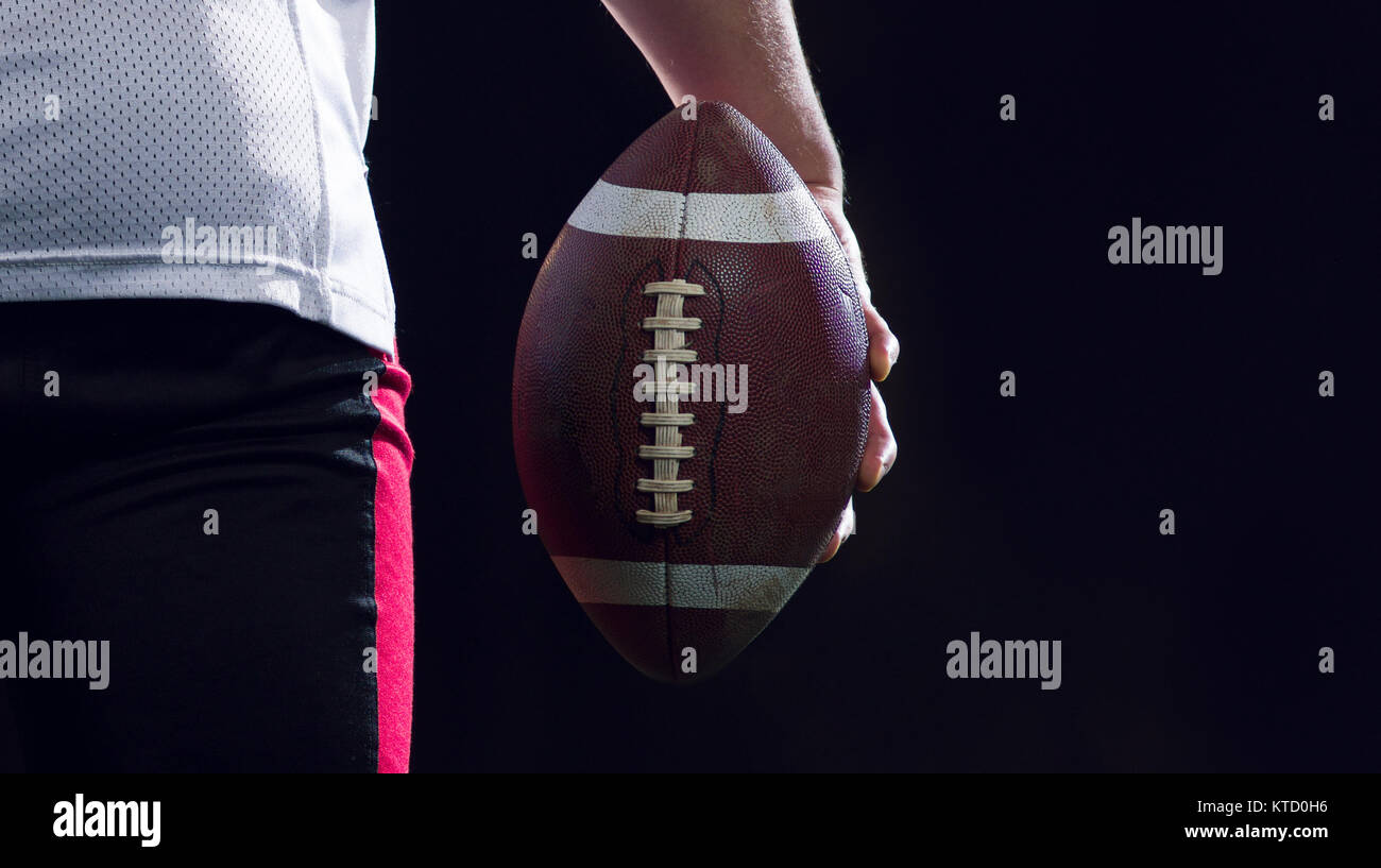 rear view of young confident American football player on field at night ...