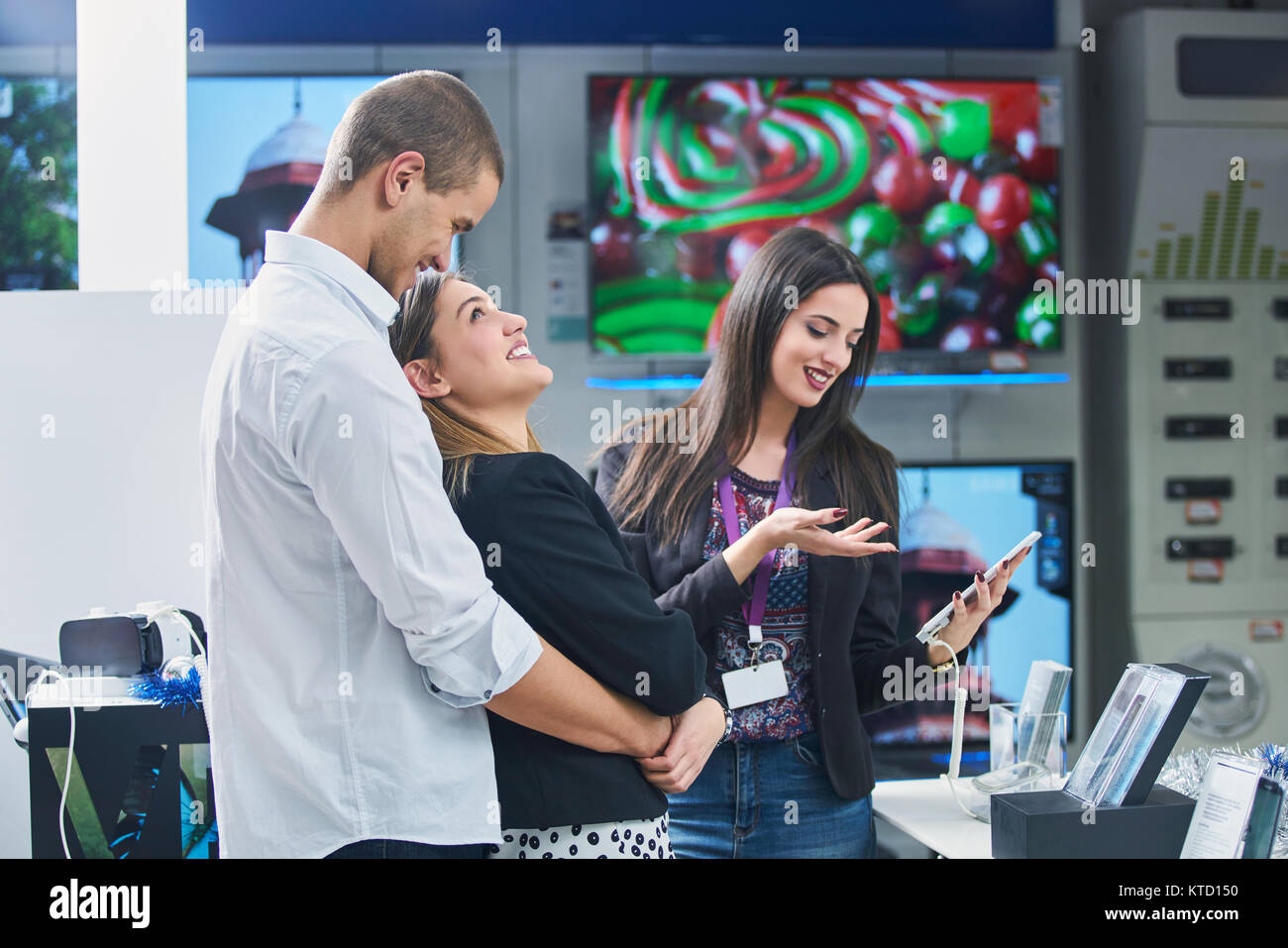 Young couple in consumer electronics store looking at latest laptop ...