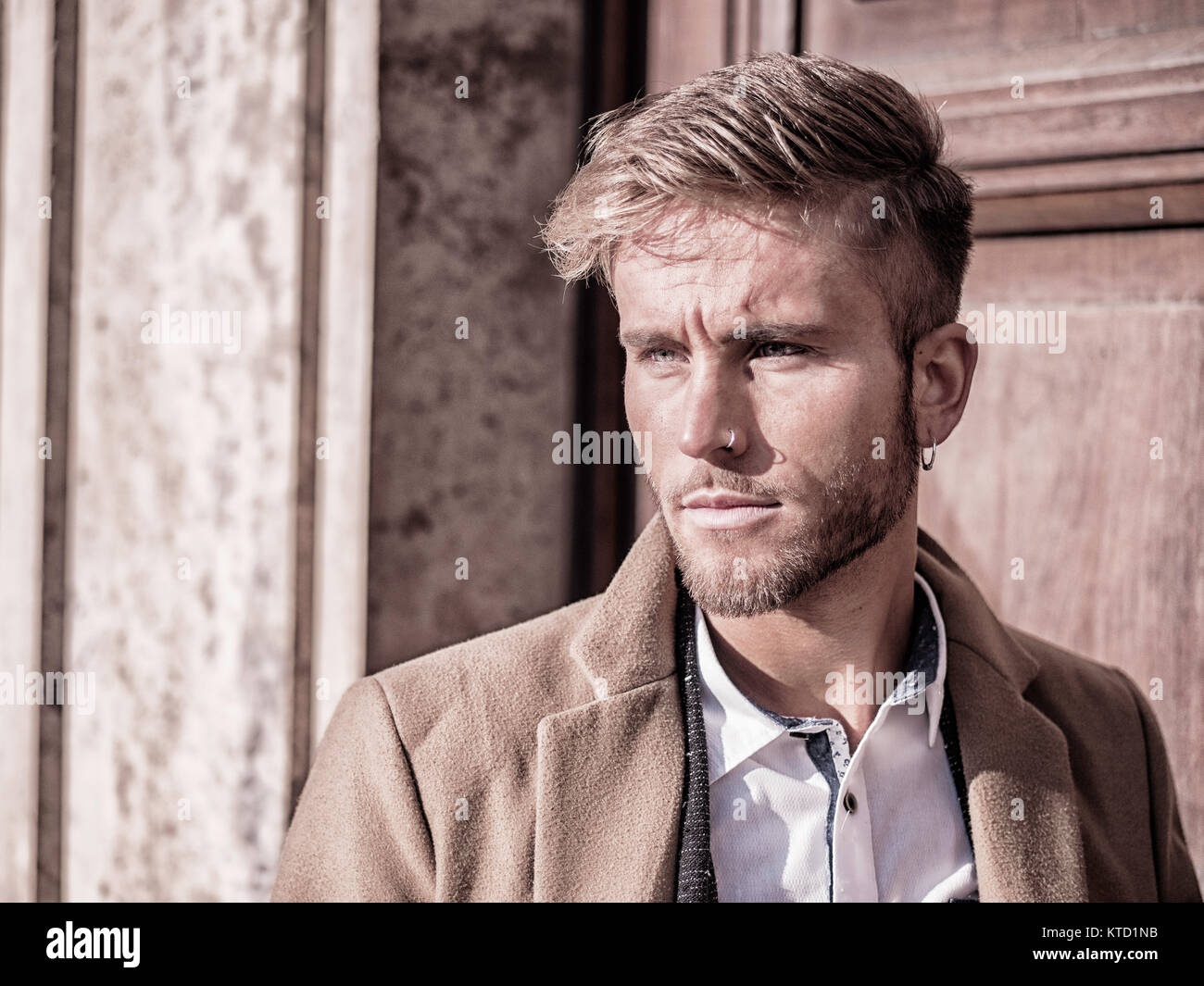 Handsome trendy blond man standing outdoor in European city setting ...