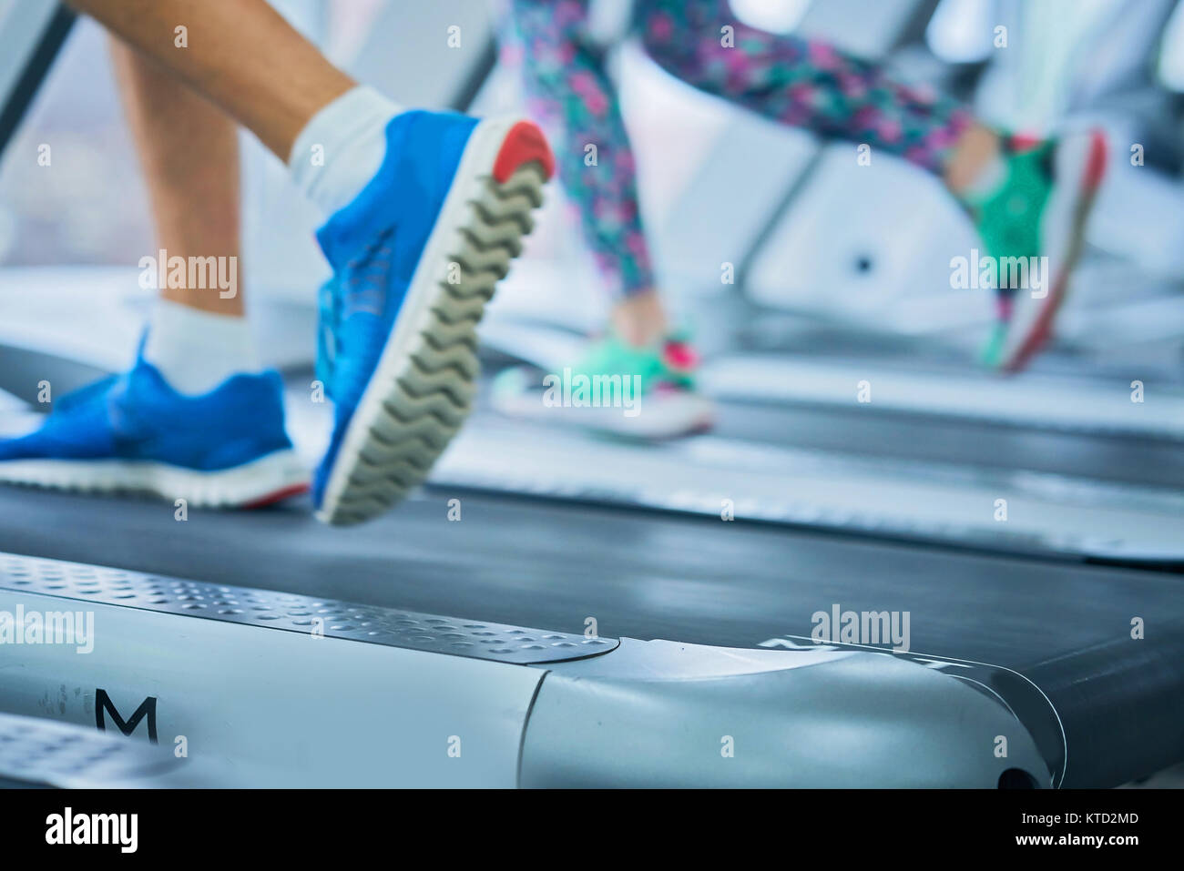 Female muscular feet in sneakers running on the treadmill at the gym ...