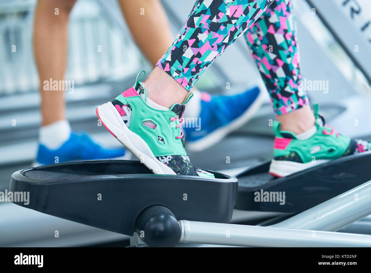 Female muscular feet in sneakers running on the treadmill at the gym ...