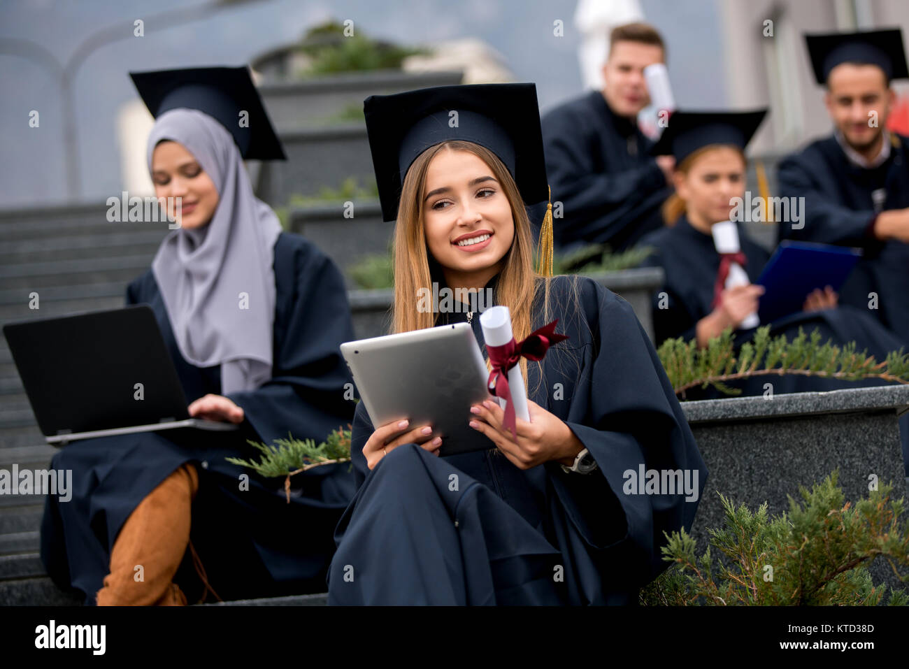 Pretty young graduate with collegues, teamwork, diploma Stock Photo - Alamy