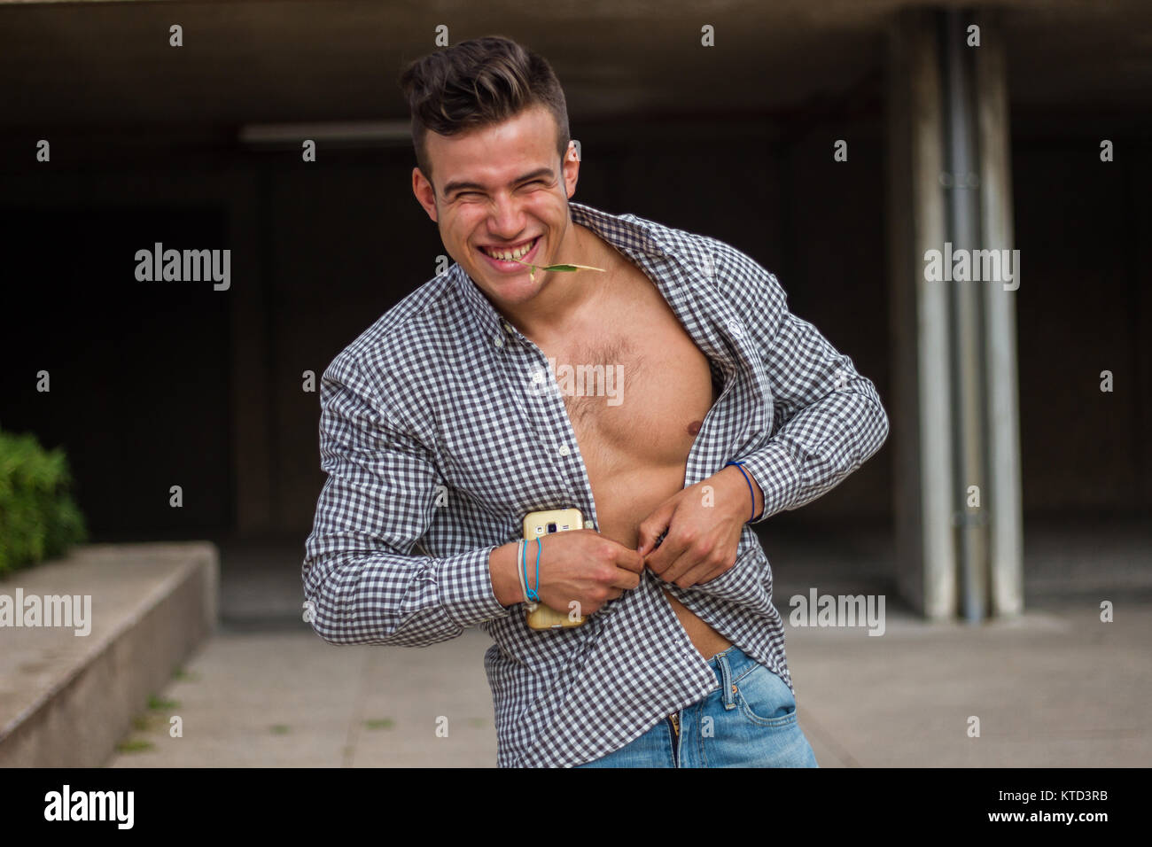 Strong and muscular young man posing on the street. He wears a shirt ...
