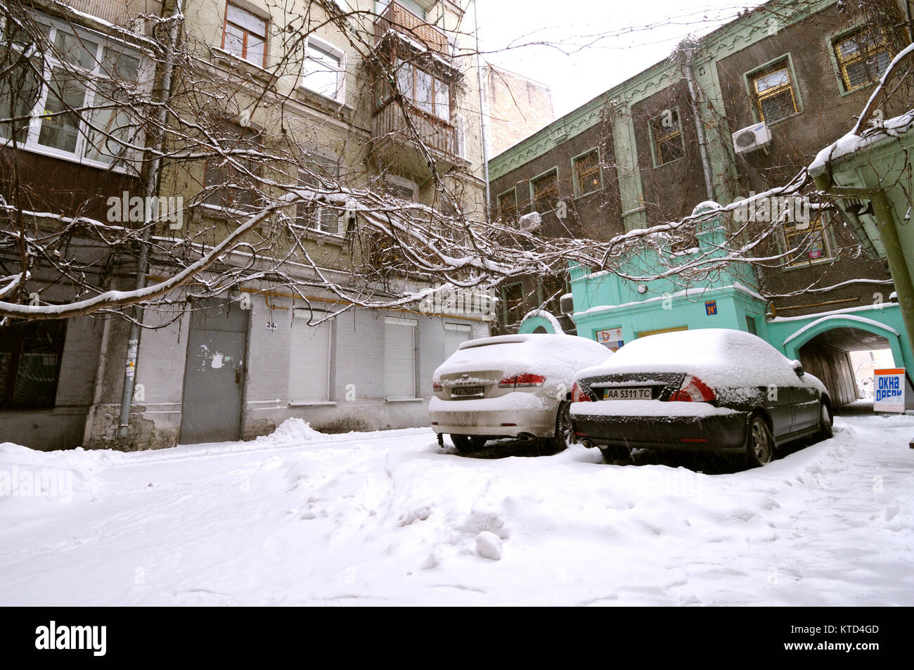 City after blizzard. Cars parked on a street of Kyiv covered with snow ...
