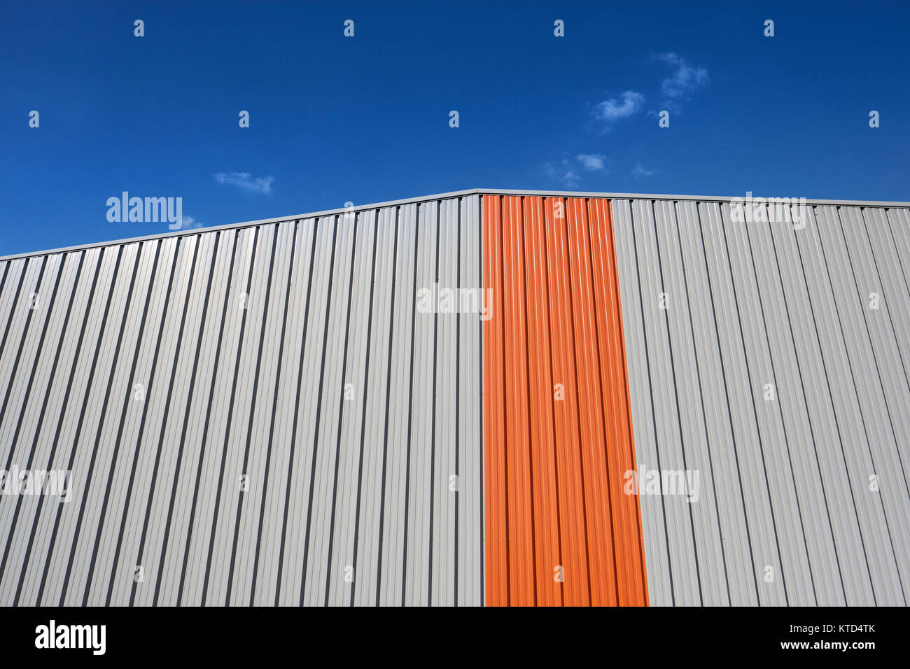 An graphic orange stripe on a modern building detail against a blue sky ...
