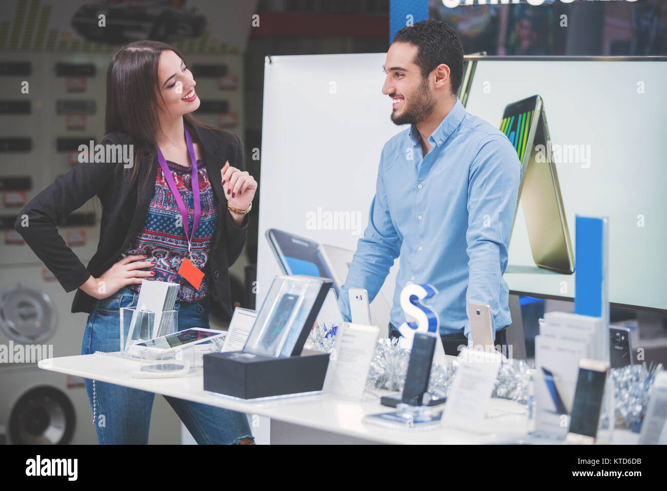 Young couple in consumer electronics store looking at latest laptop ...