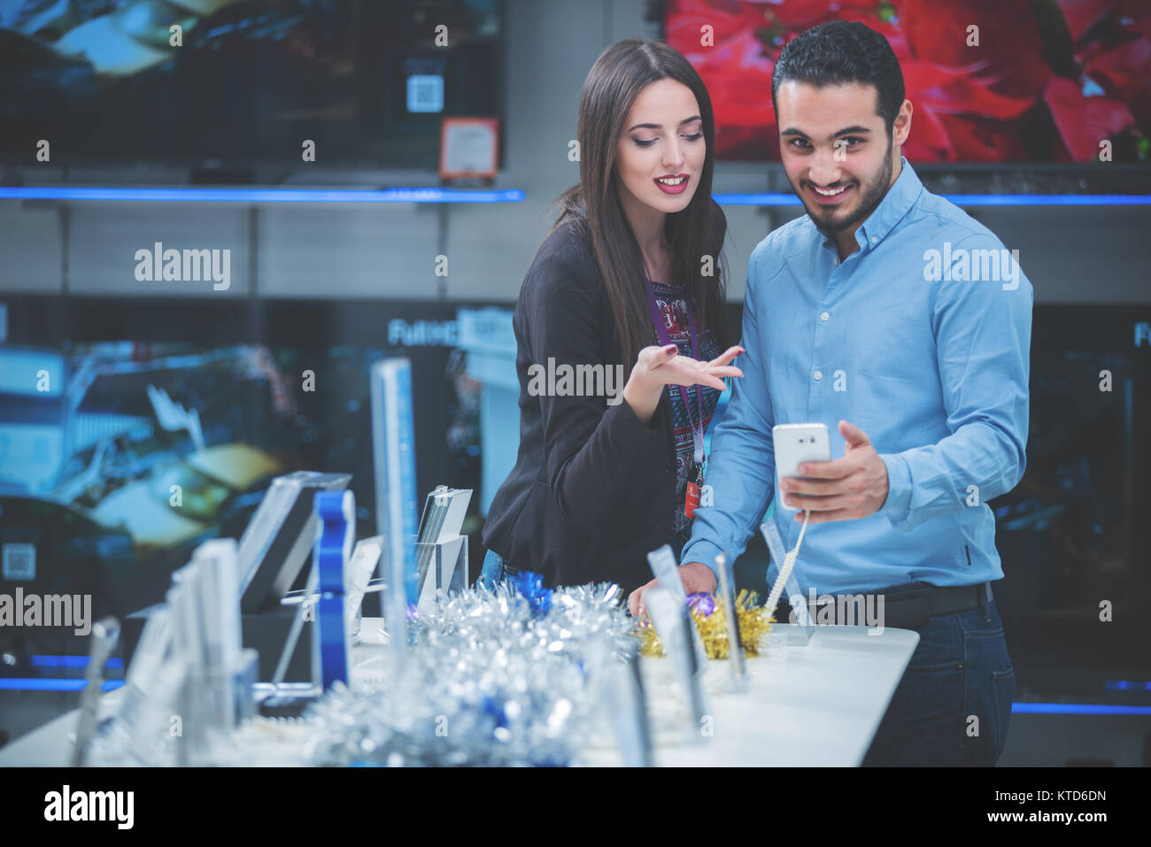 Young couple in consumer electronics store looking at latest laptop ...