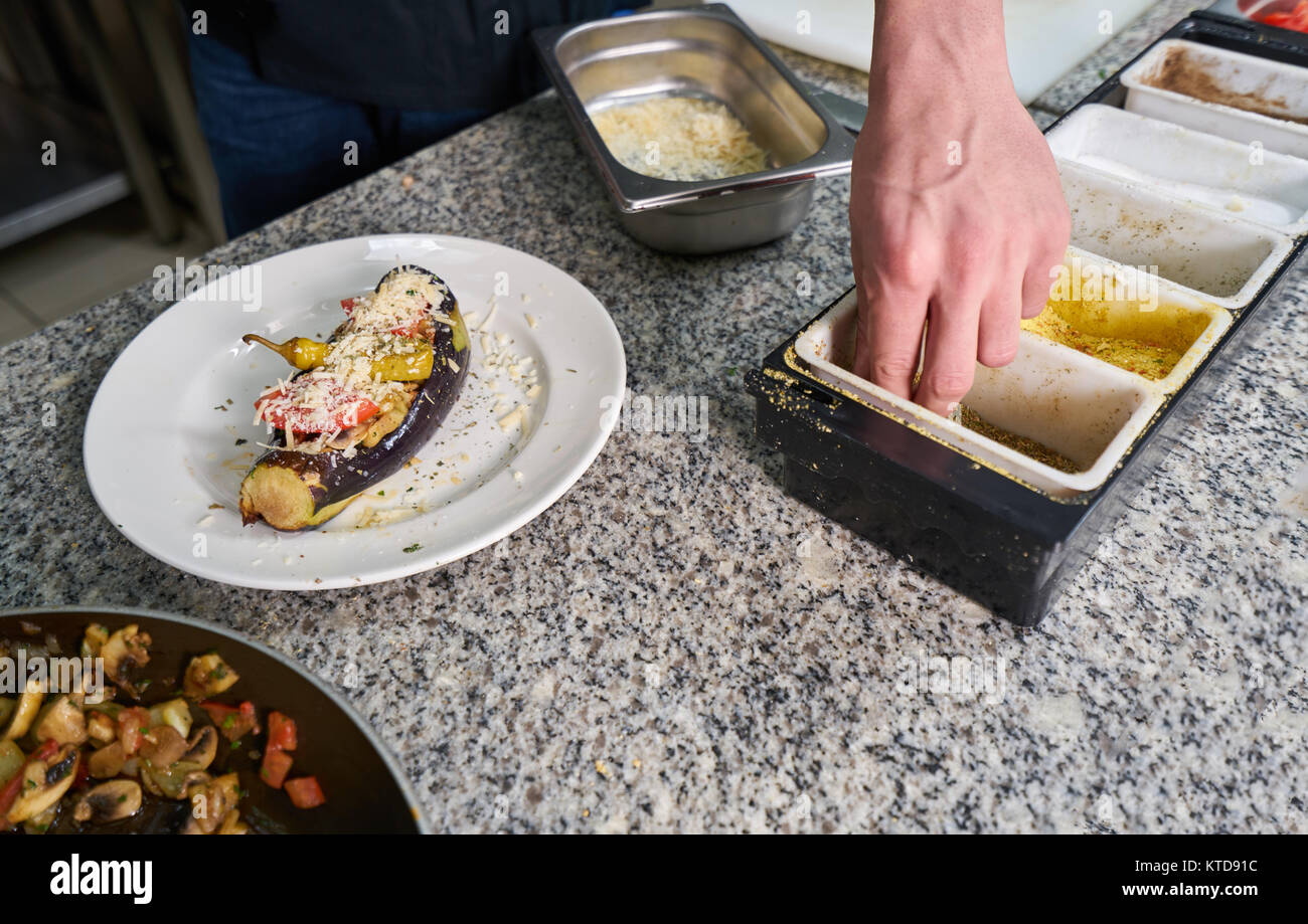 Chef sprinkling spices on dish in commercial kitchen Stock Photo - Alamy