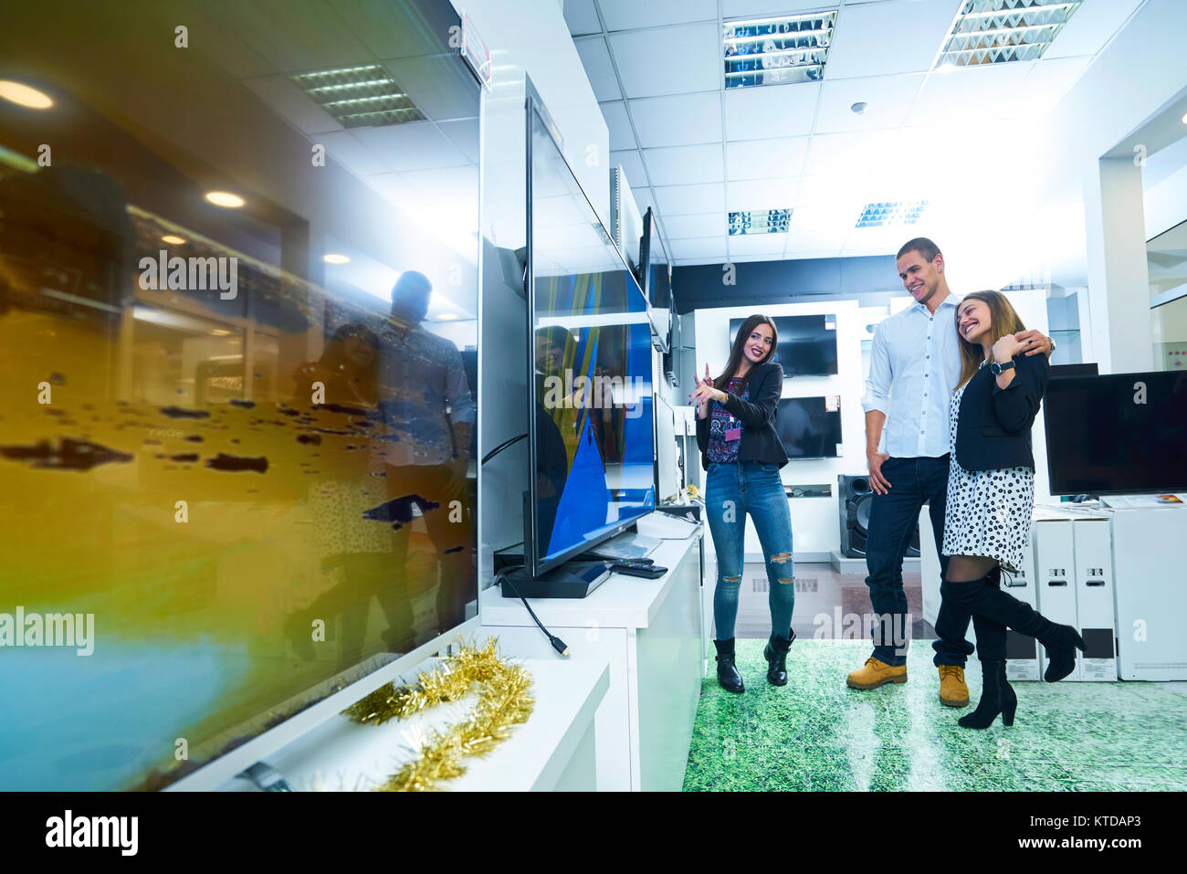 Young couple in consumer electronics store looking at latest laptop ...