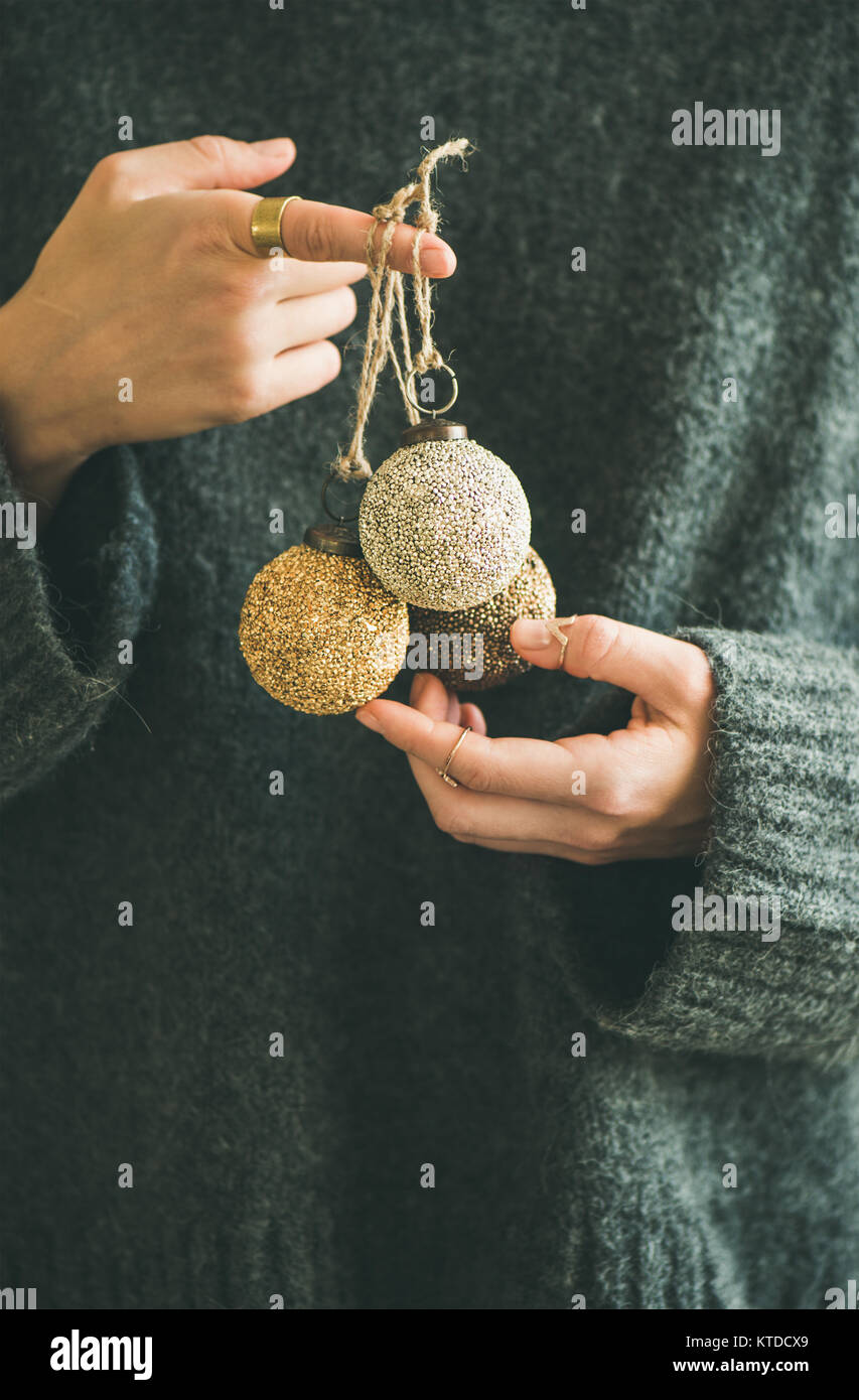 Woman in grey sweater holding decorative golden balls in hands Stock ...