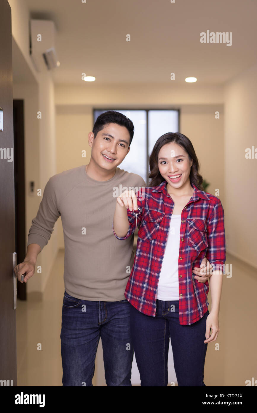 Happy young couple handing their new home keys and open house door ...