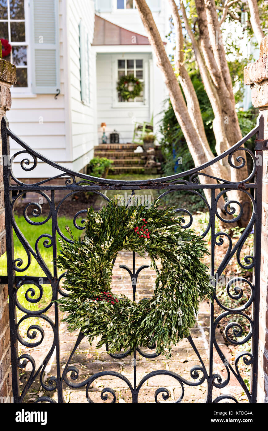 A Christmas wreath hangs from a wrought iron gate on a historic home ...