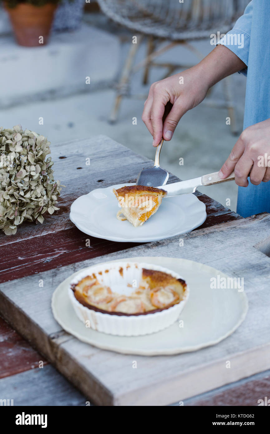 Italy, woman putting piece of tartlet on dish, partial view Stock Photo ...
