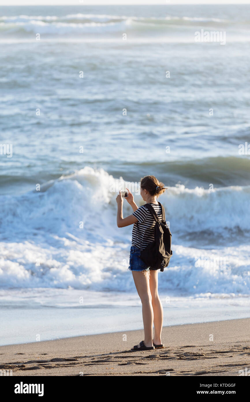 Indonesia, Bali, young woman taking cell phone picture on the beach ...
