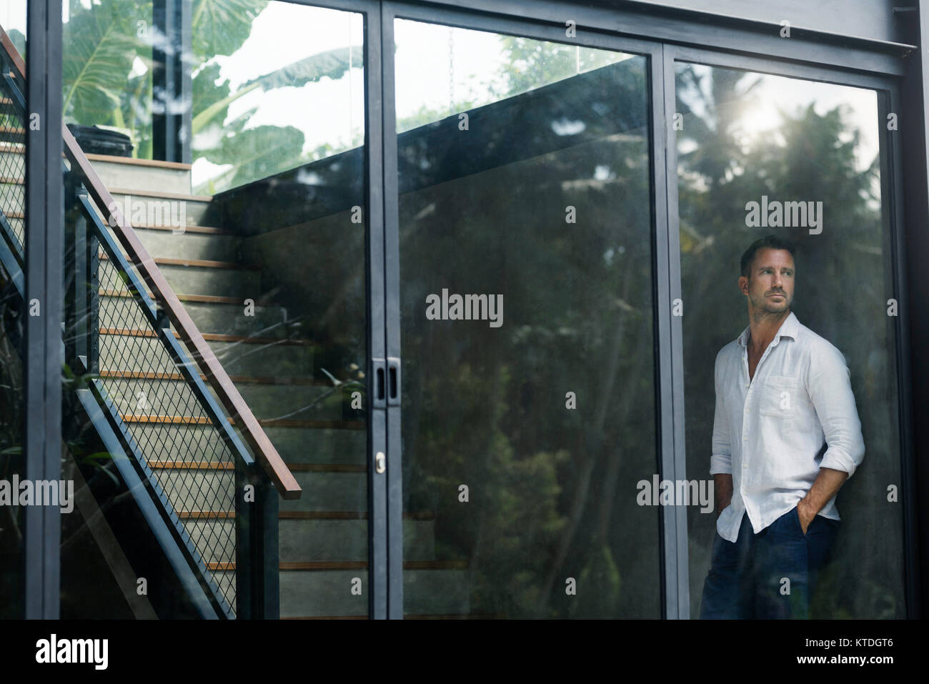 Mature man standing in his modern house, looking through window Stock ...