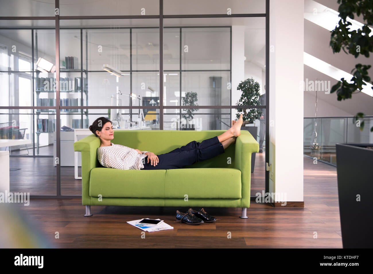 Businesswoman taking a nap lying on a couch in the office Stock Photo ...