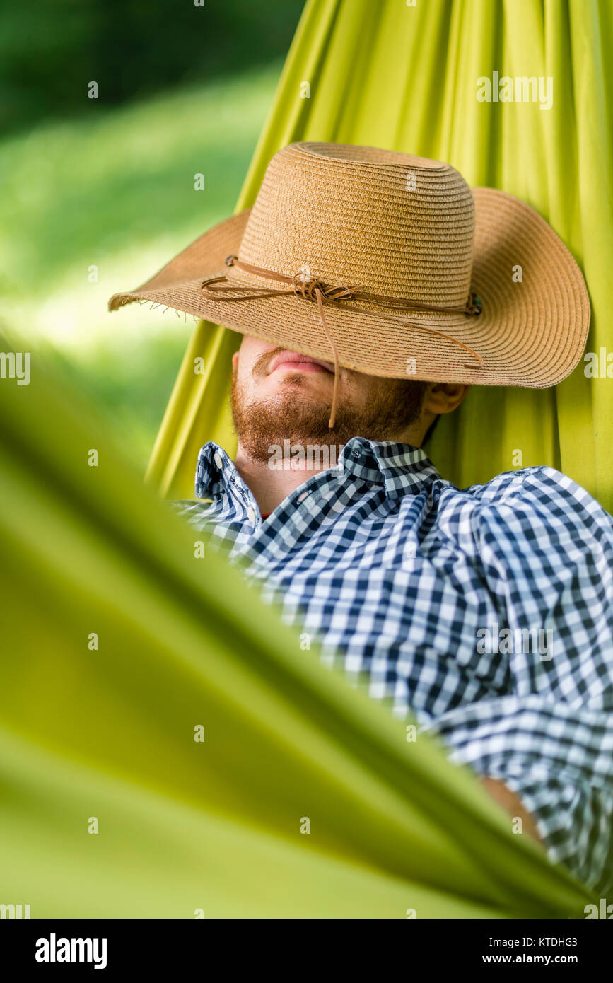 Man relaxing in hammock with hat on his face Stock Photo - Alamy