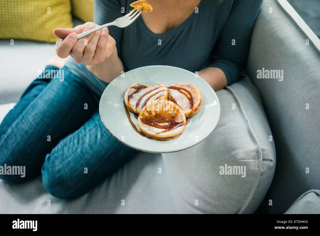 Close-up of woman sitting on couch eating pancakes Stock Photo - Alamy