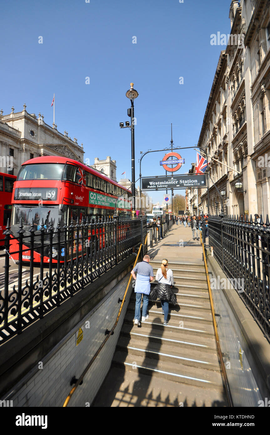 People leaving Westminster Underground station with red London buses in ...