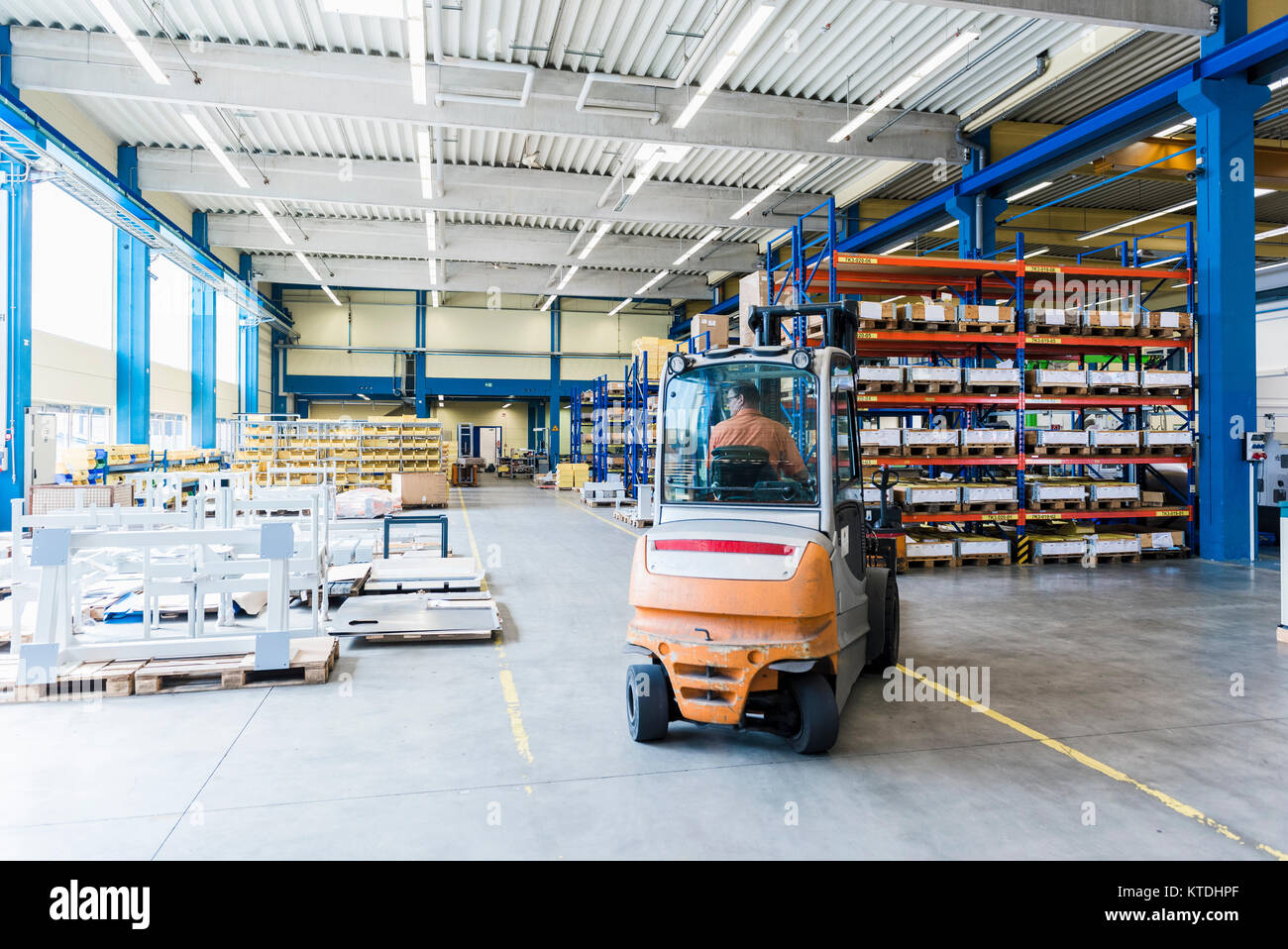 Man on forklift in factory warehouse Stock Photo - Alamy